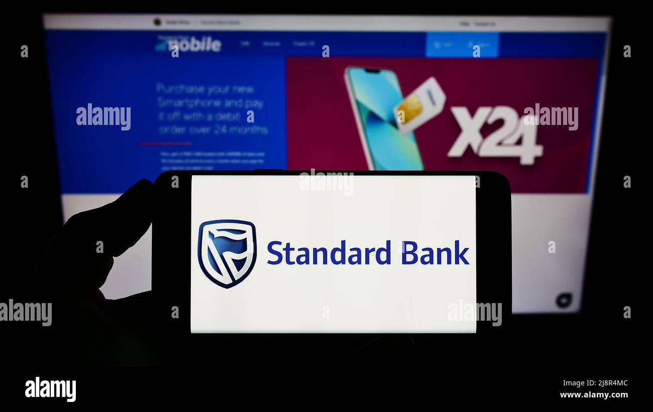 Person holding smartphone with logo of South African company Standard ...