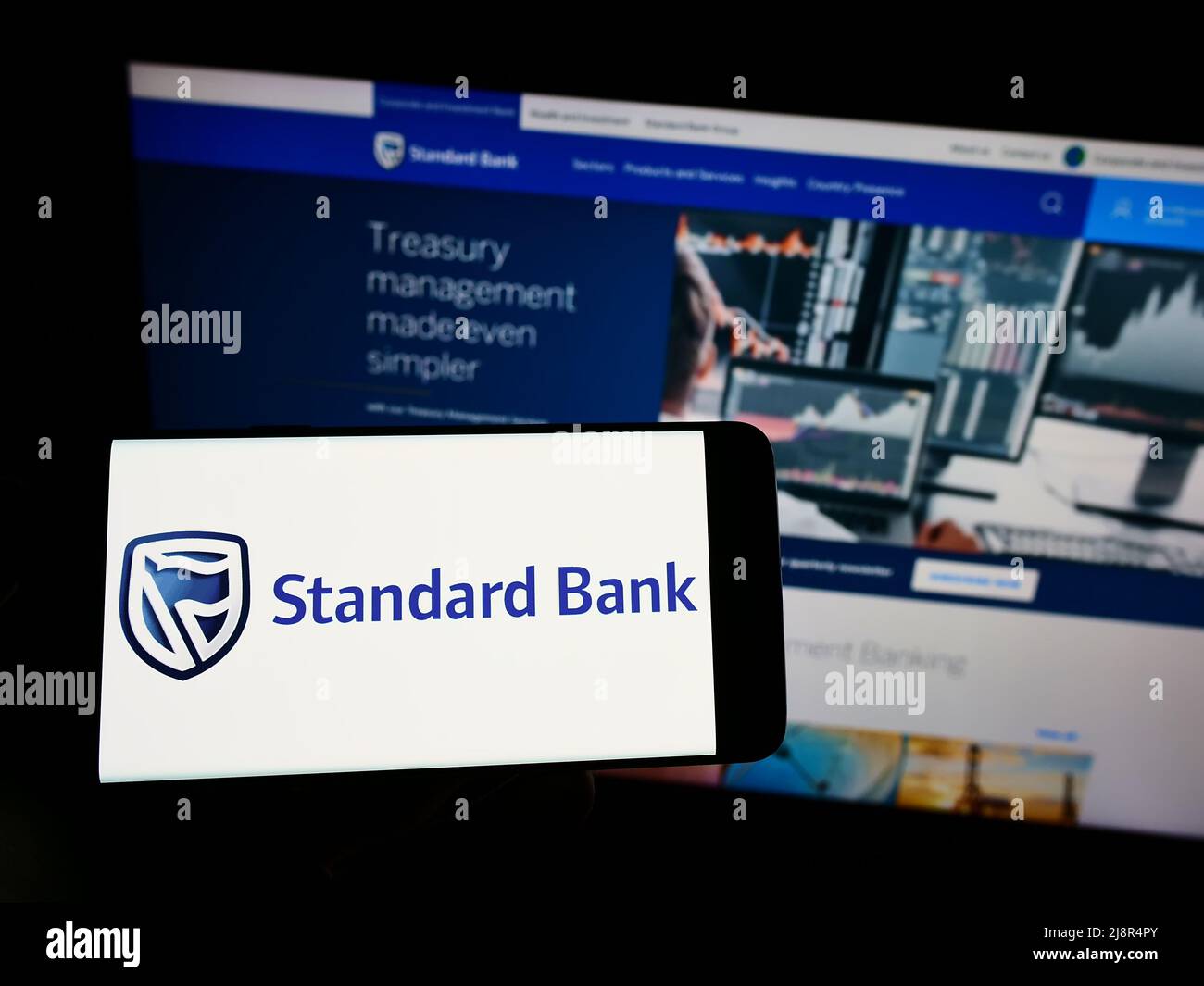 Person holding cellphone with logo of South African company Standard ...