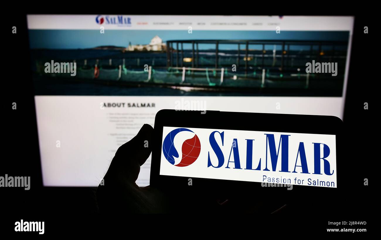 Person holding smartphone with logo of Norwegian fish farm company ...