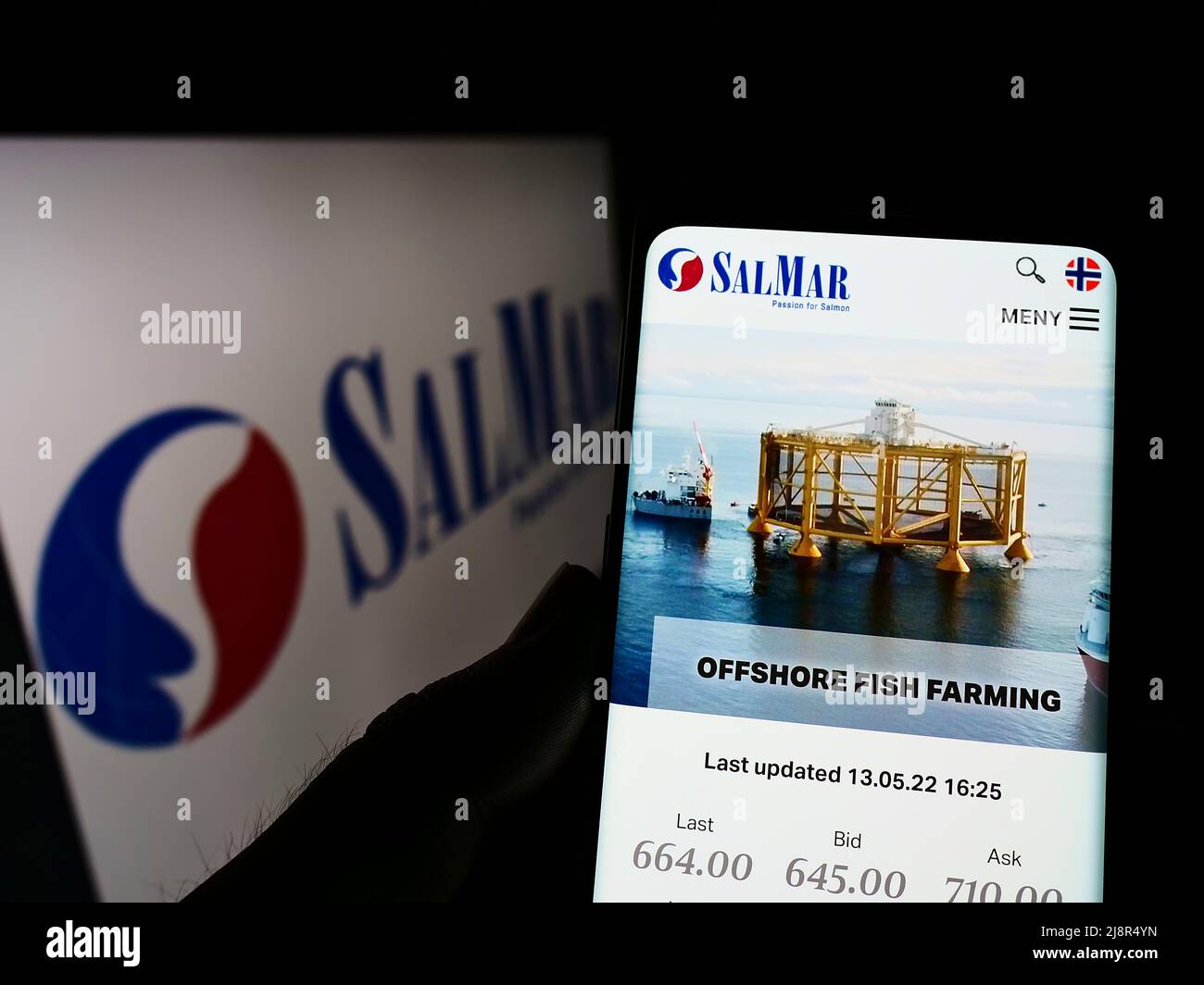 Person holding cellphone with website of Norwegian fish farm company ...