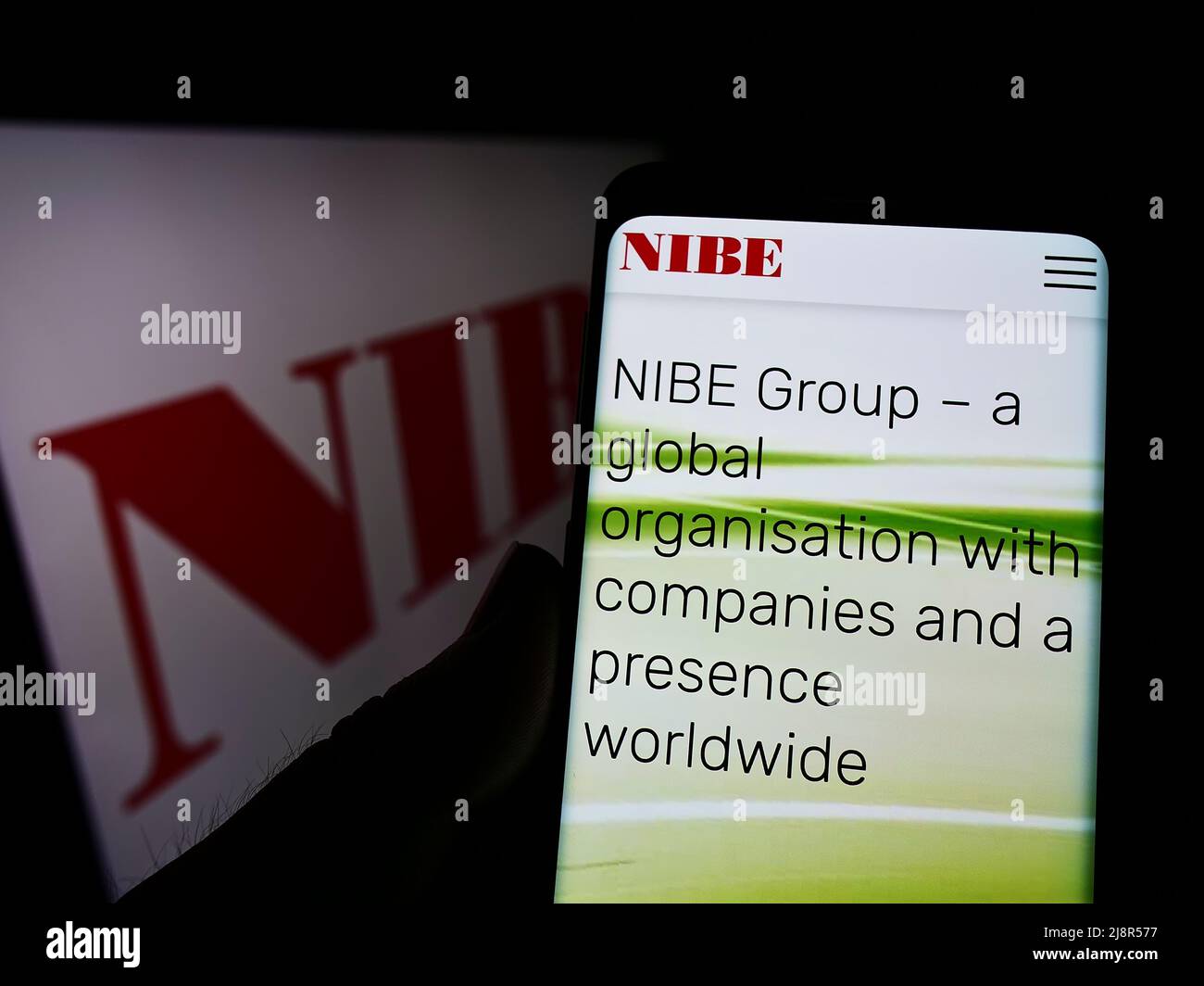 Person holding smartphone with website of heating system company NIBE ...