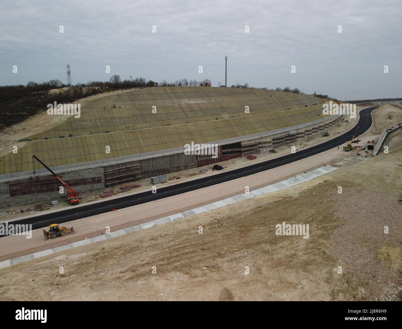 Workers reinforce the slope over the new road. Road construction in ...