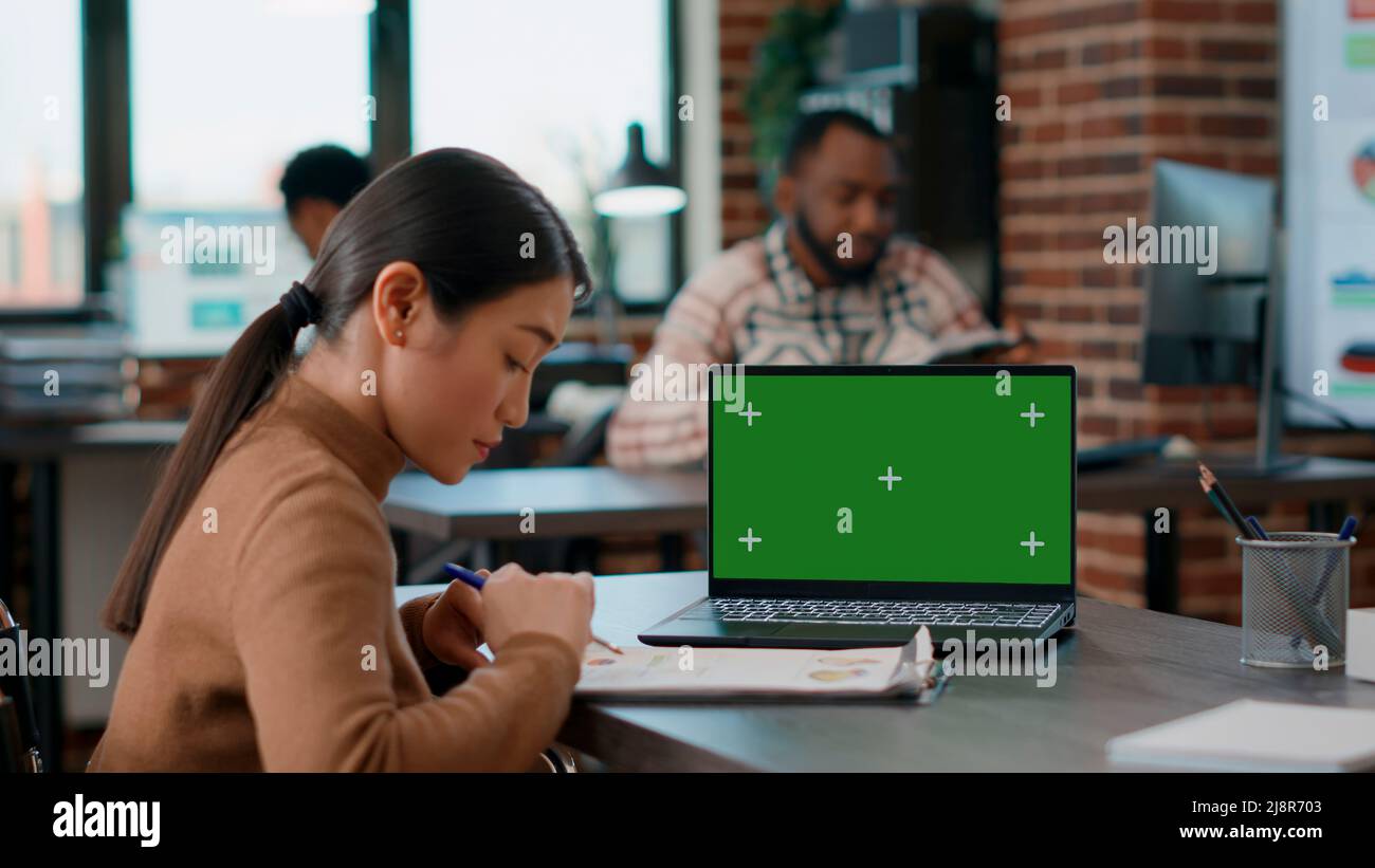Office Worker Analyzing Charts On Paper And Looking At Greenscreen On