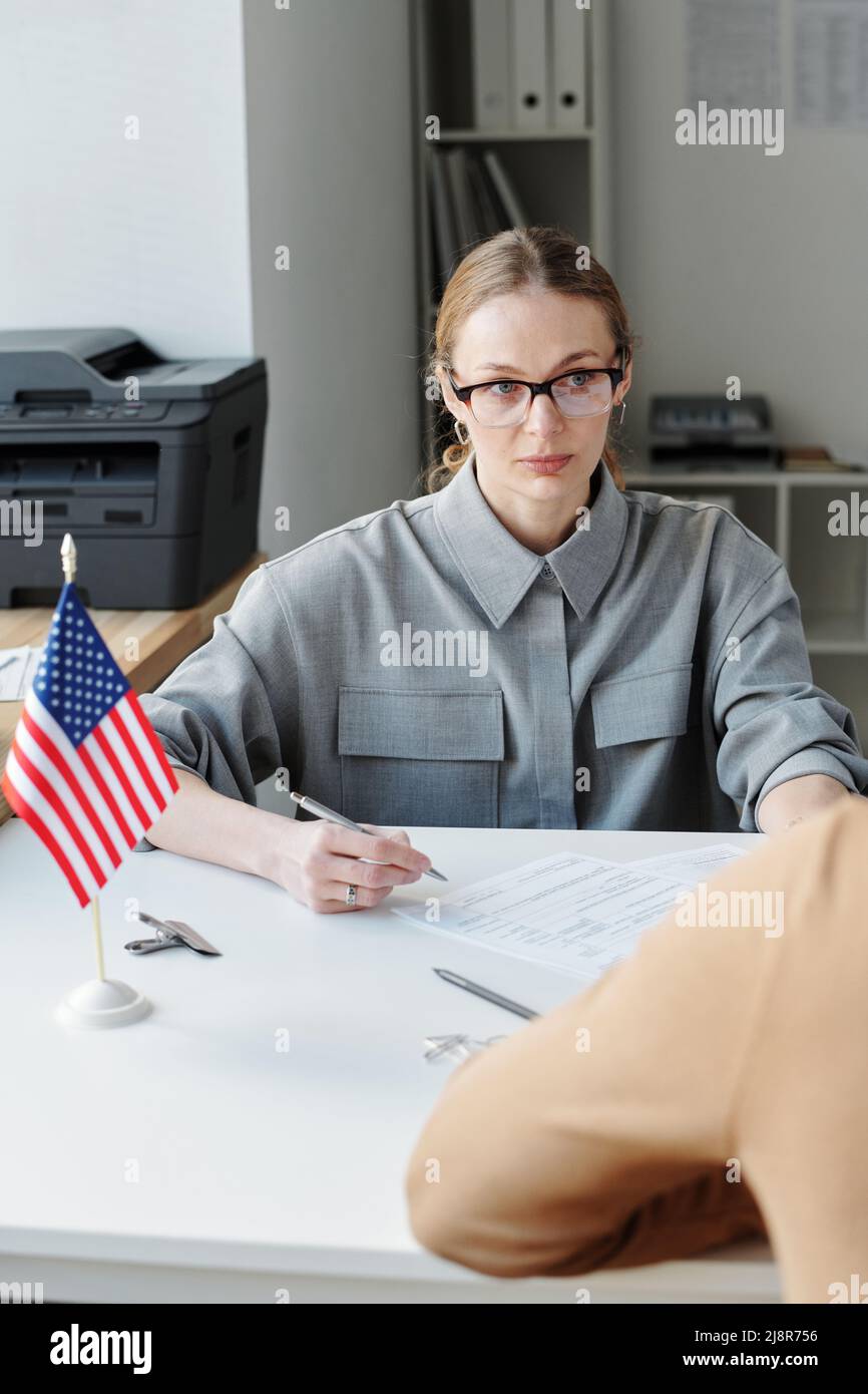 Vertical shot of serious woman working in US embassy or consulate ...
