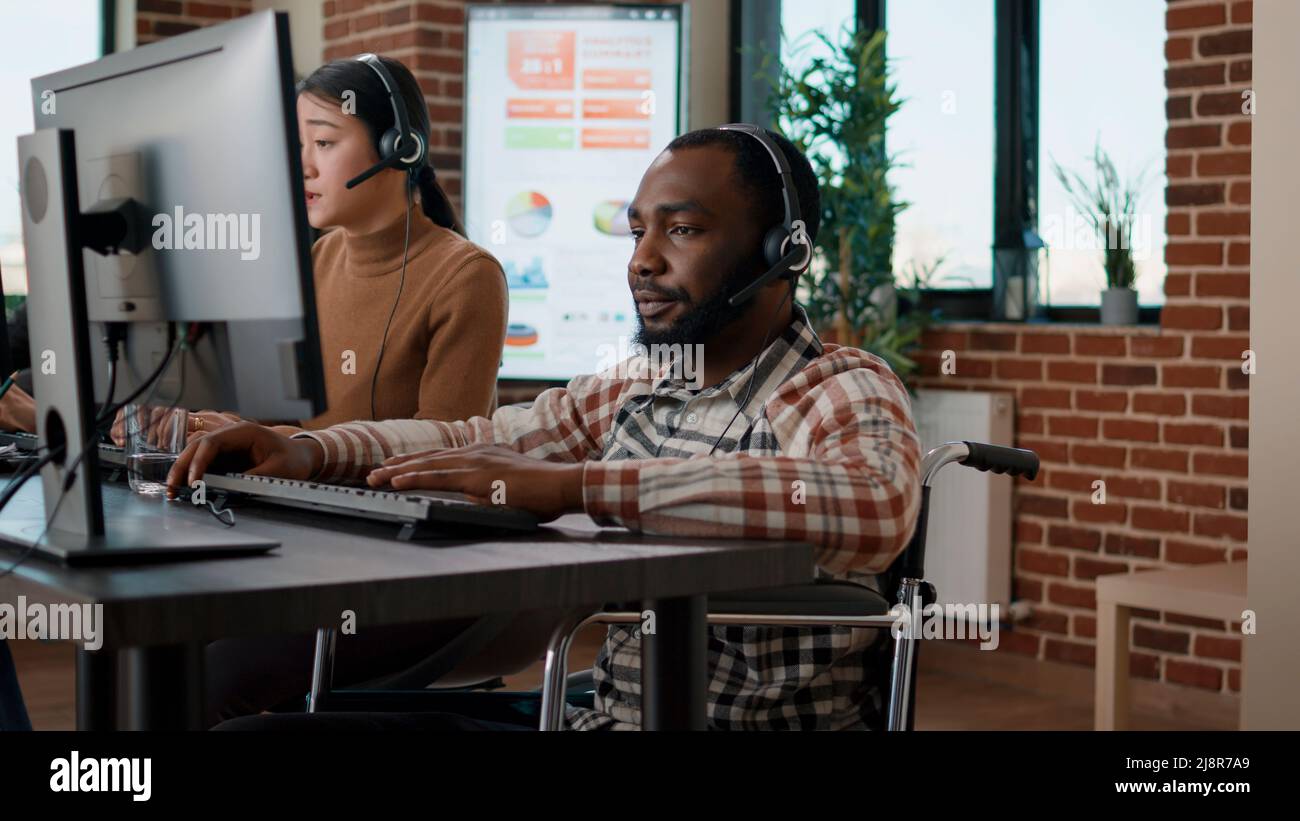 African american man in wheelchair answering helpline call at customer ...