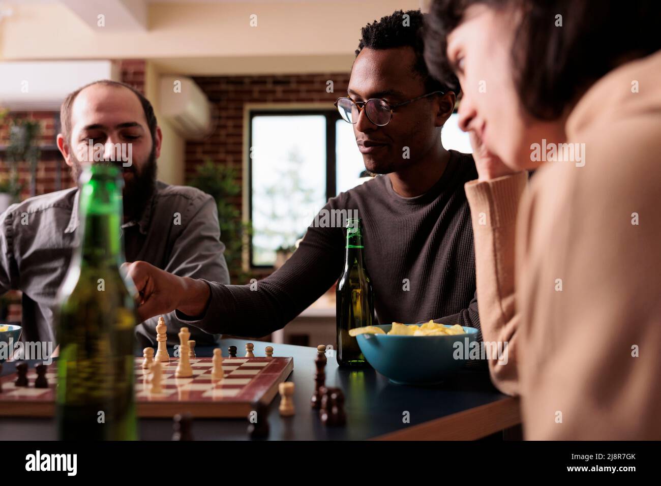 Smart looking man moving chess piece on board while sitting at table in ...