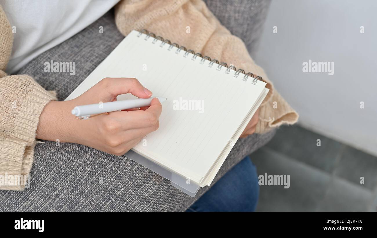 Female taking notes on spiral notepad, hand writing something on blank ...