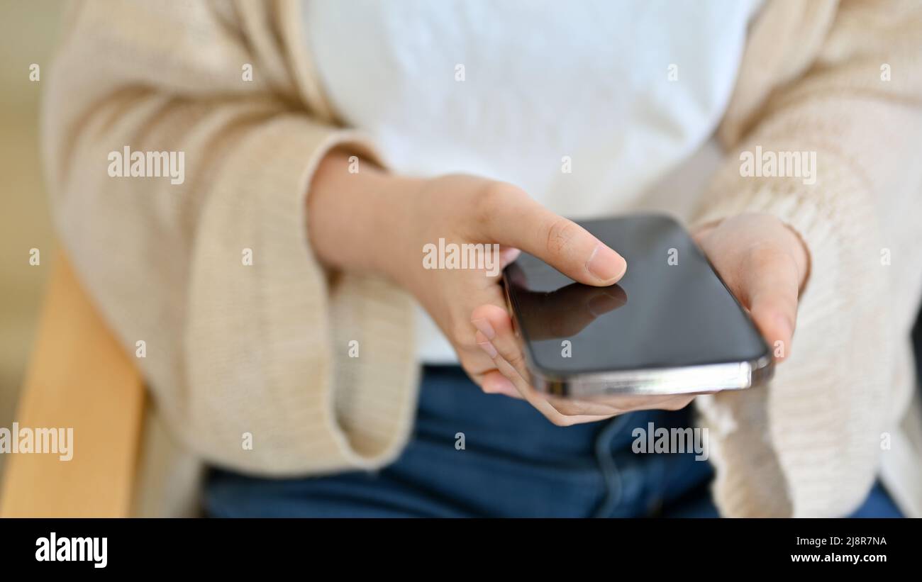 Close-up shot, Female in comfy casual outfit using a smartphone ...
