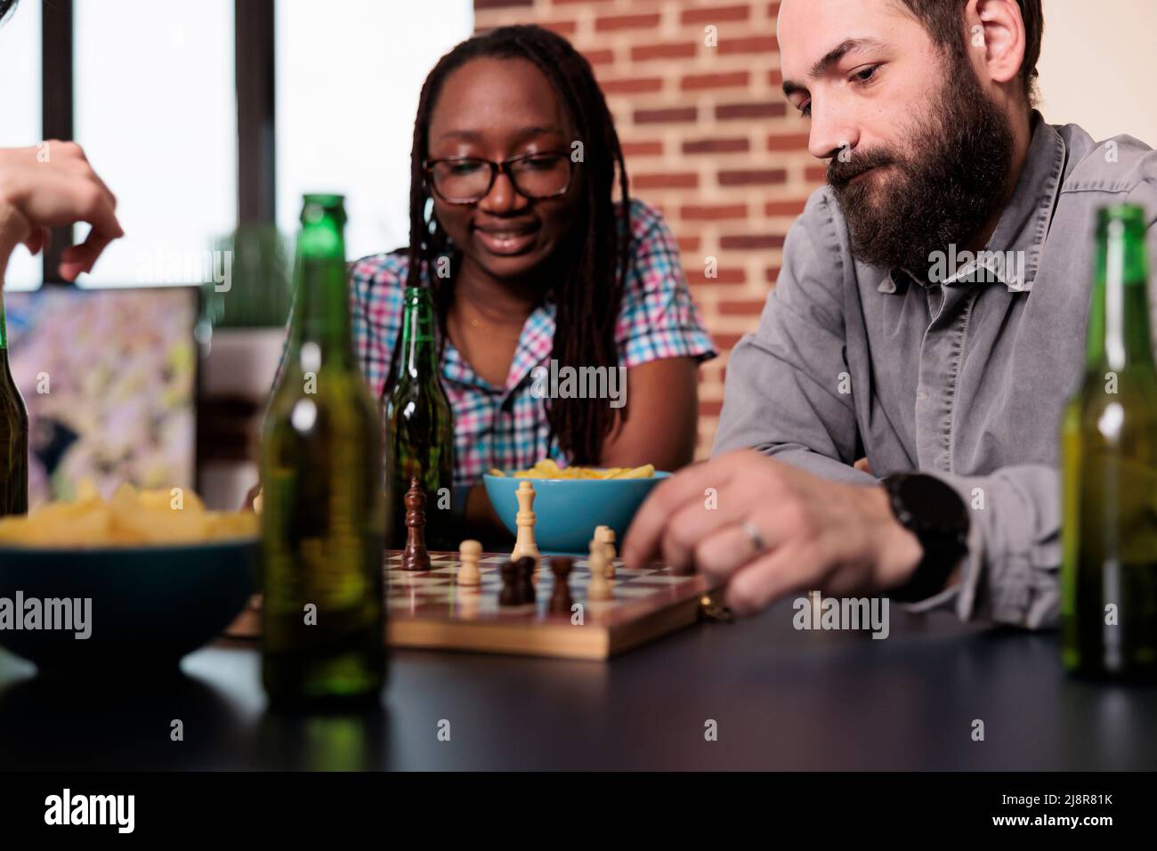 Smart multiethnic friends sitting at home while playing chess together ...