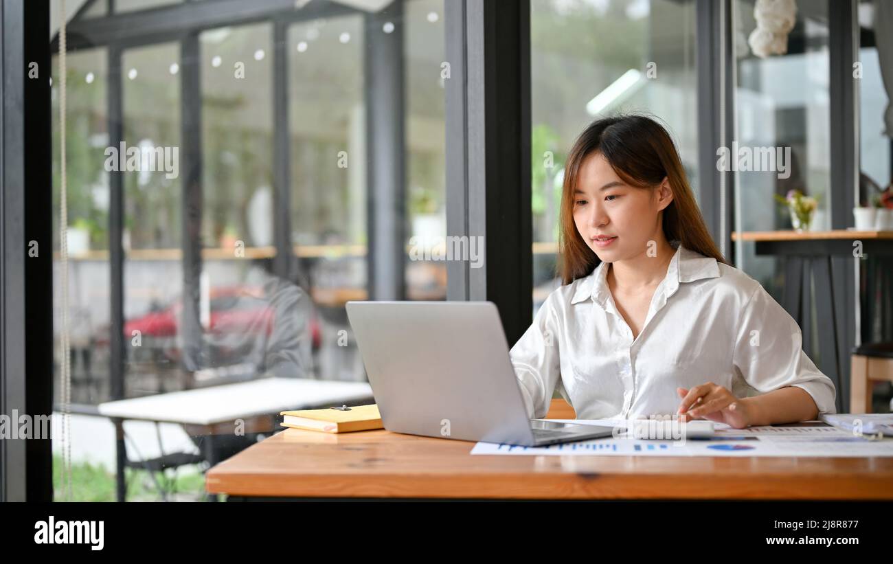 Concentrated Asian female financial analysts or businesswoman reviewing ...