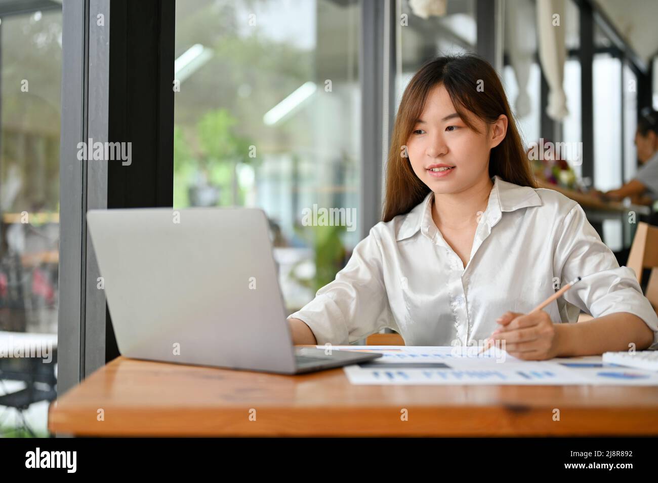 Charming Asian young female office worker using laptop computer ...