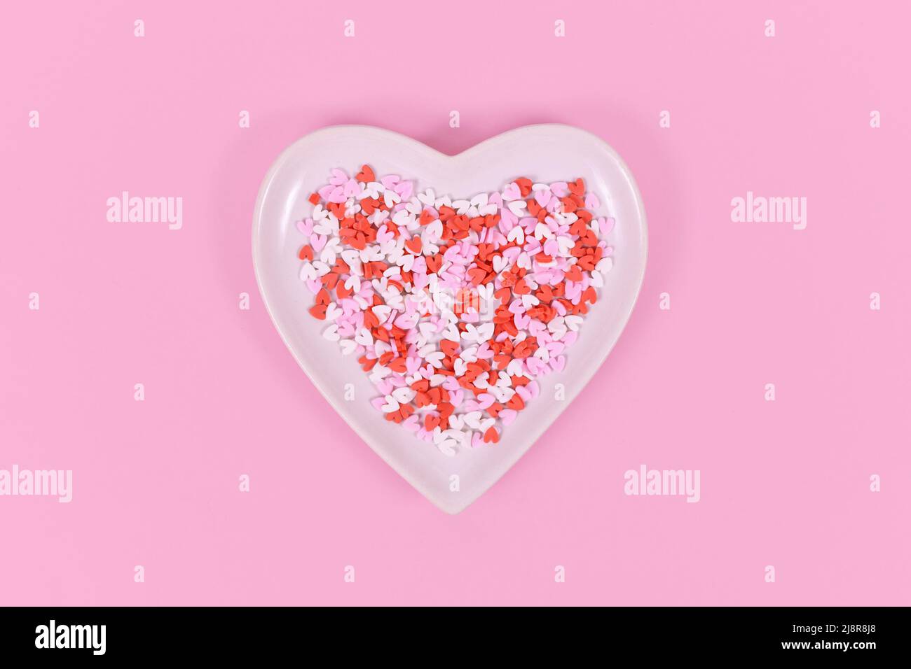 Plate with heart shaped sugar sprinkles on pink background Stock Photo ...