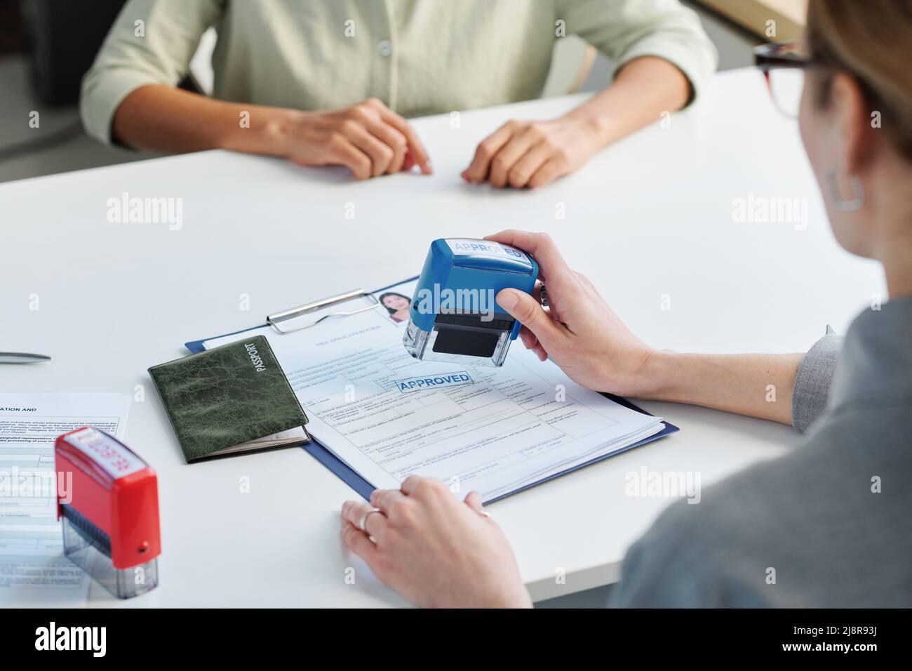 Unrecognizable woman working in embassy office giving approval to visa ...