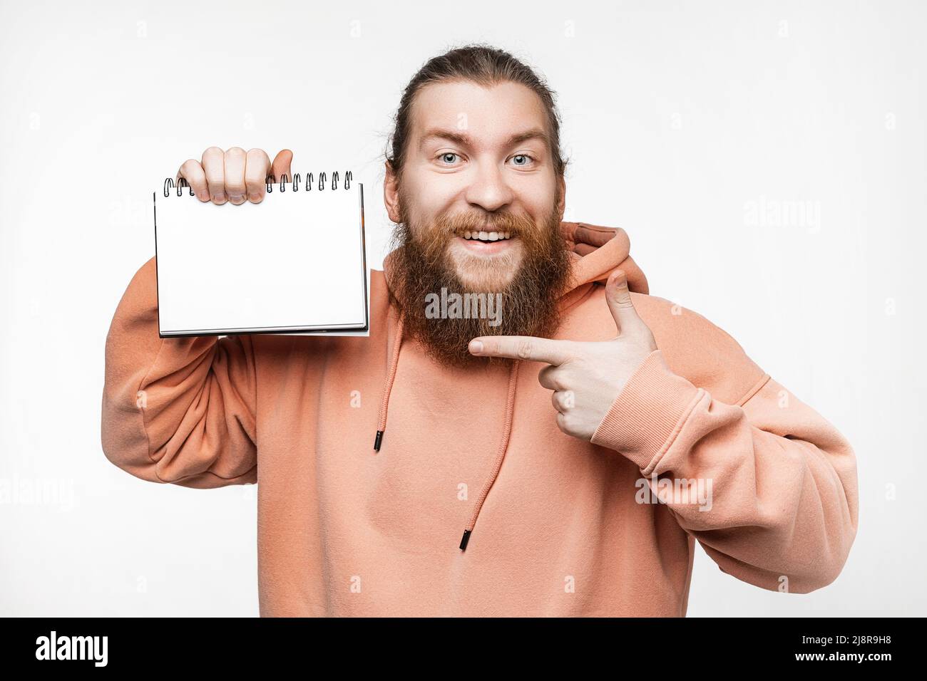 Scandinavian handsome happy man holding notepad and points to paper ...