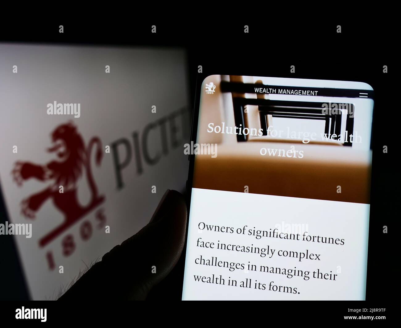 Person holding cellphone with webpage of Swiss banking company Banque ...