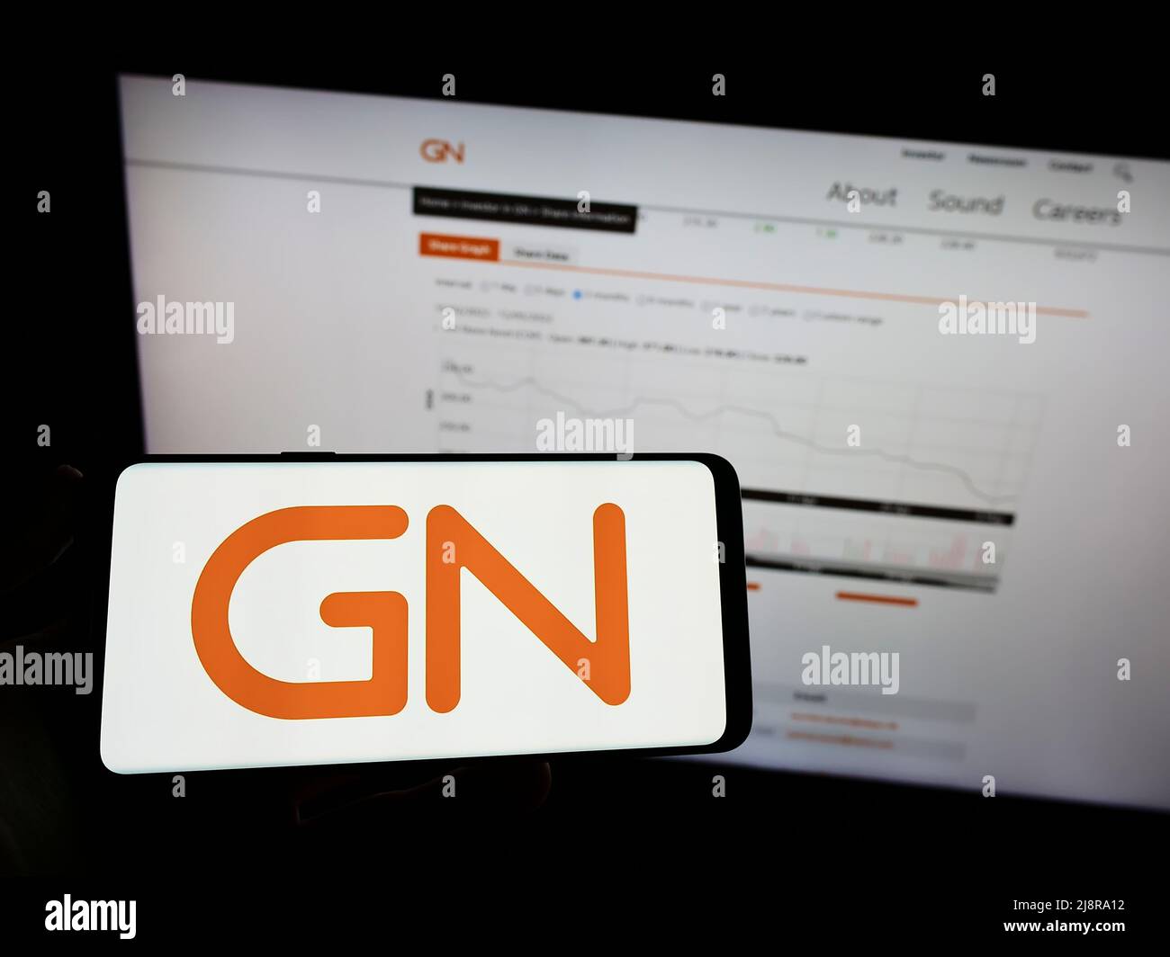 Person holding mobile phone with logo of Danish electronics company GN ...