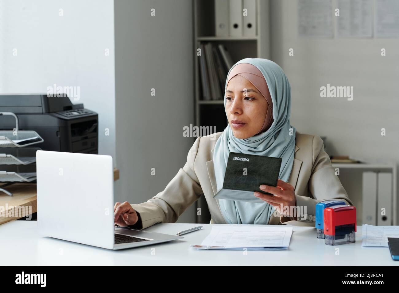 Modern young adult Muslim woman wearing hijab working as consular ...