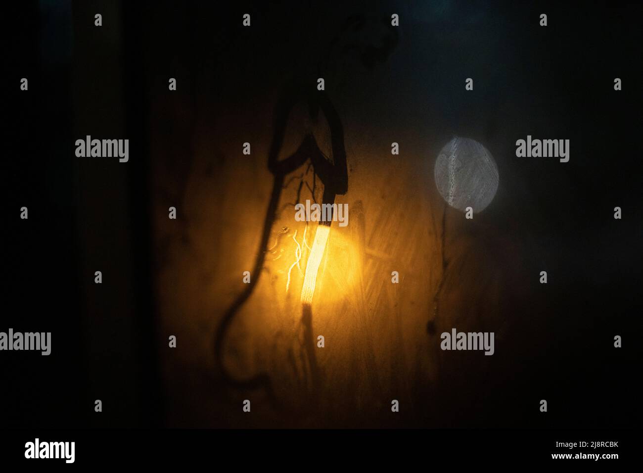 Drawing on wet glass. Foggy window. Warm light is reflected in surface ...