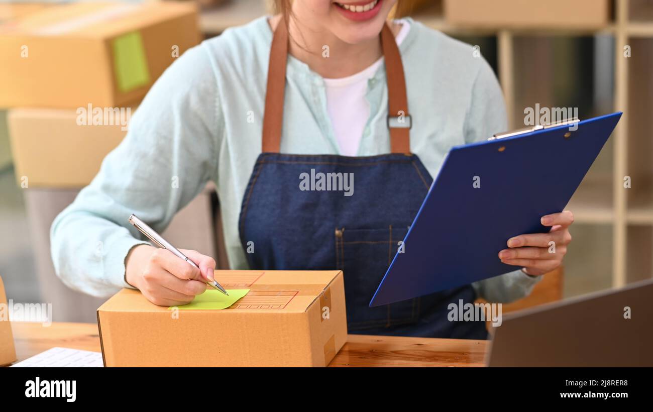 Small business entrepreneur working at home office, writing address on ...