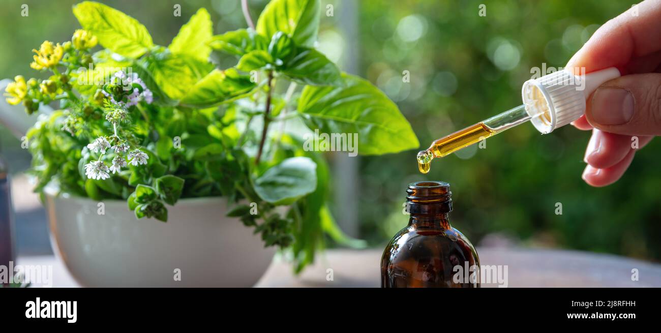 Essential oil drop falling in a glass bottle, close up. Alternative ...