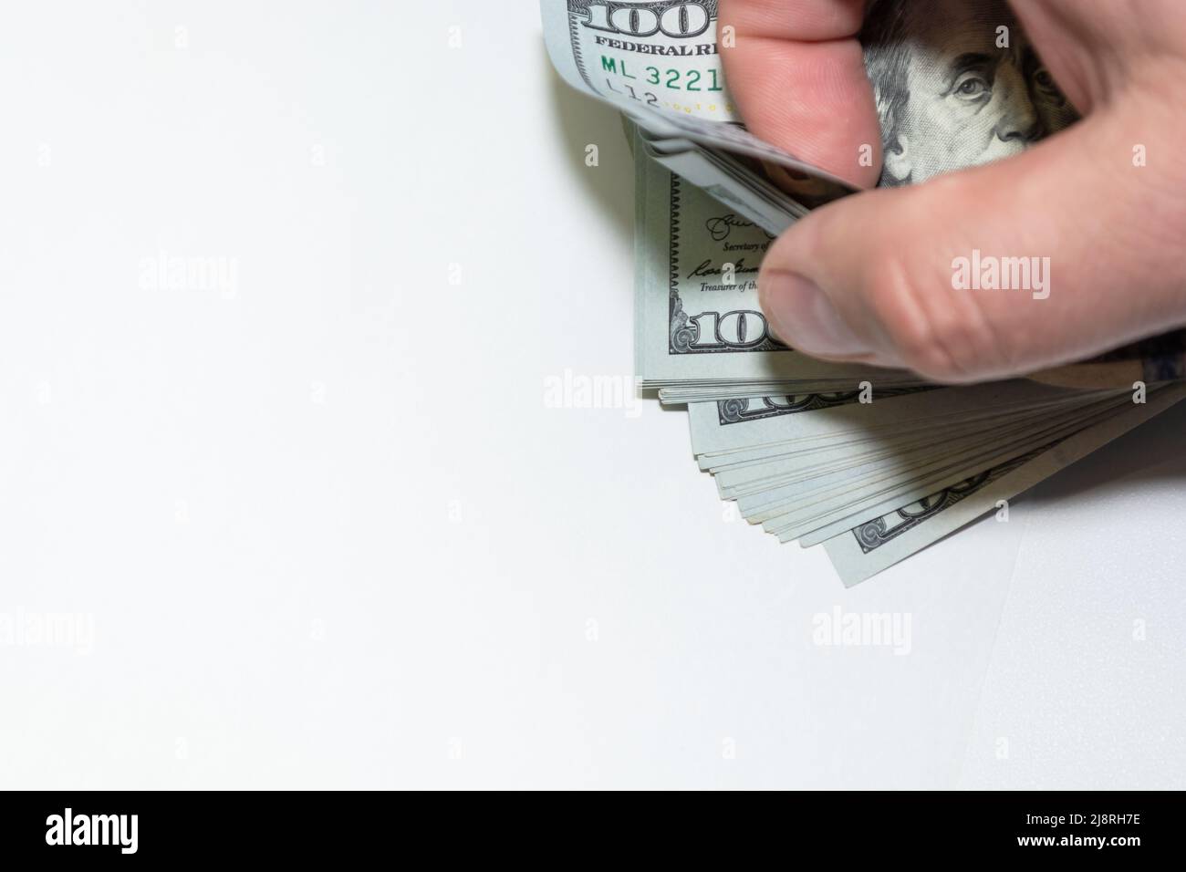 A man counts 100 dollar bills with his hand on a white background. Money and business Stock ...