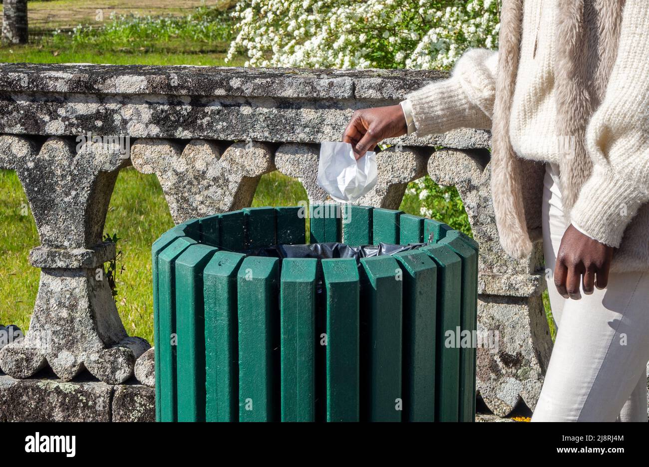young woman throwing a tissue into a rubbish bin in a park Stock Photo ...