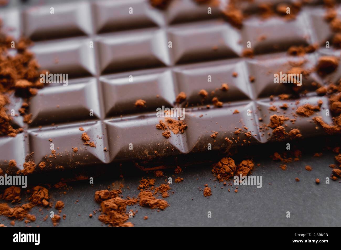 Close up view of natural cocoa on chocolate bar on black background ...