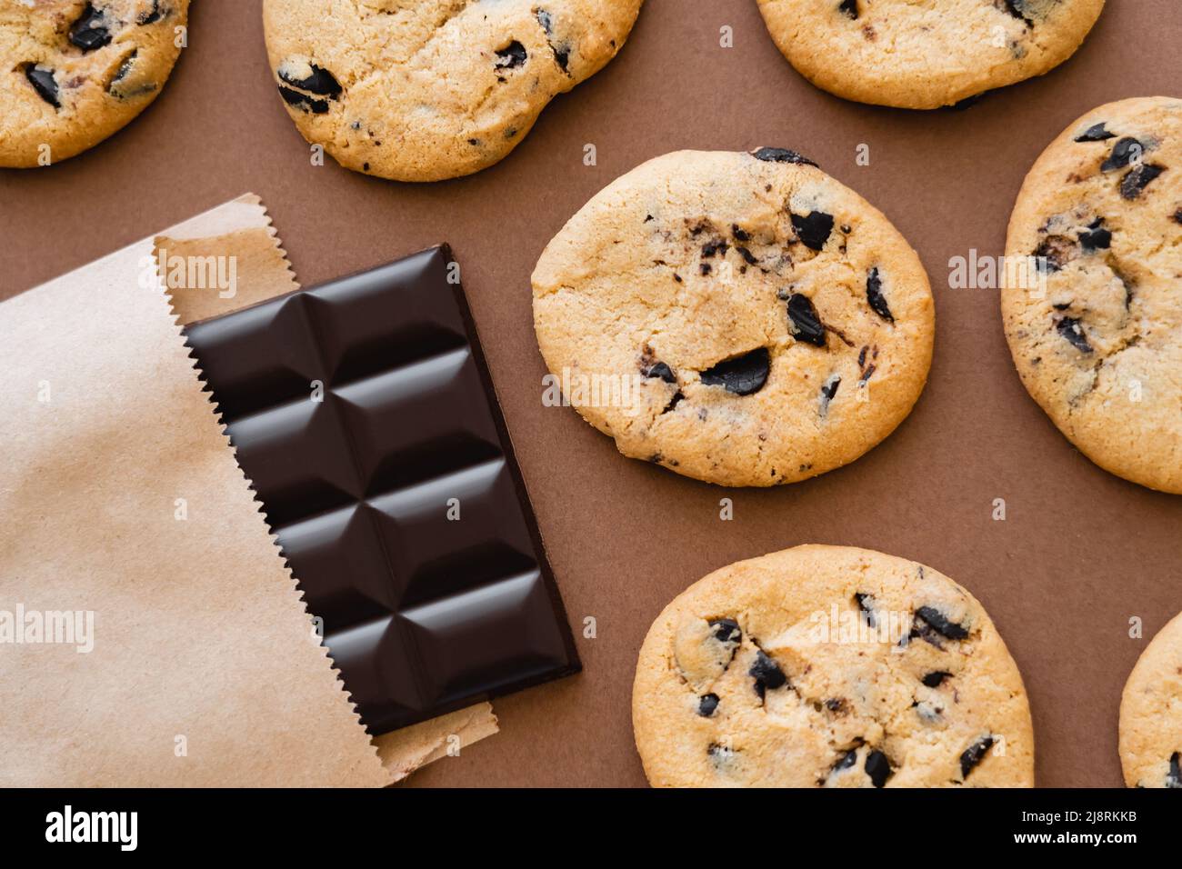 Top view of cookies near chocolate bar in craft package on brown ...