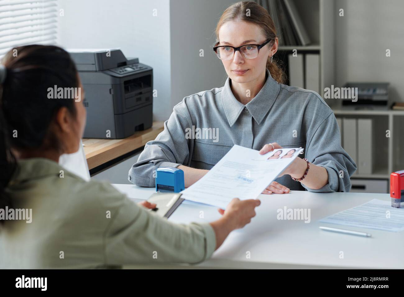 Mature Caucasian female consular officer sitting at desk in front of ...