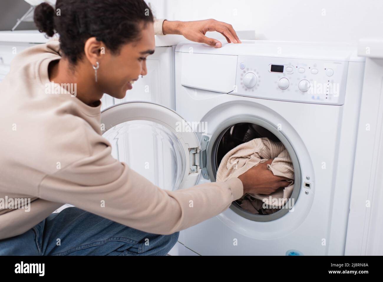 happy african american man putting laundry in washing machine Stock ...