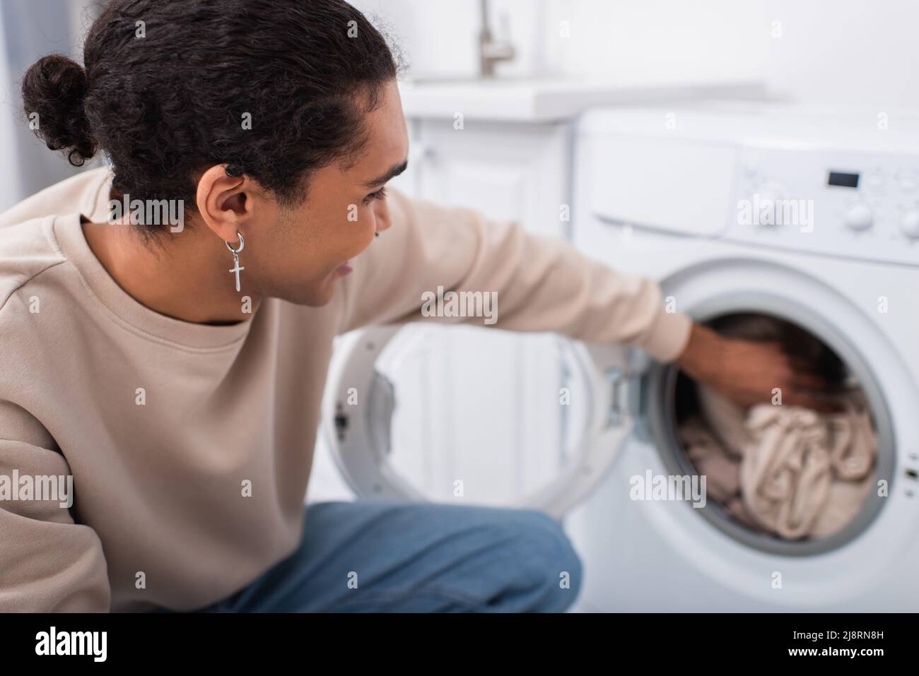 happy african american man putting clothes in washing machine Stock ...