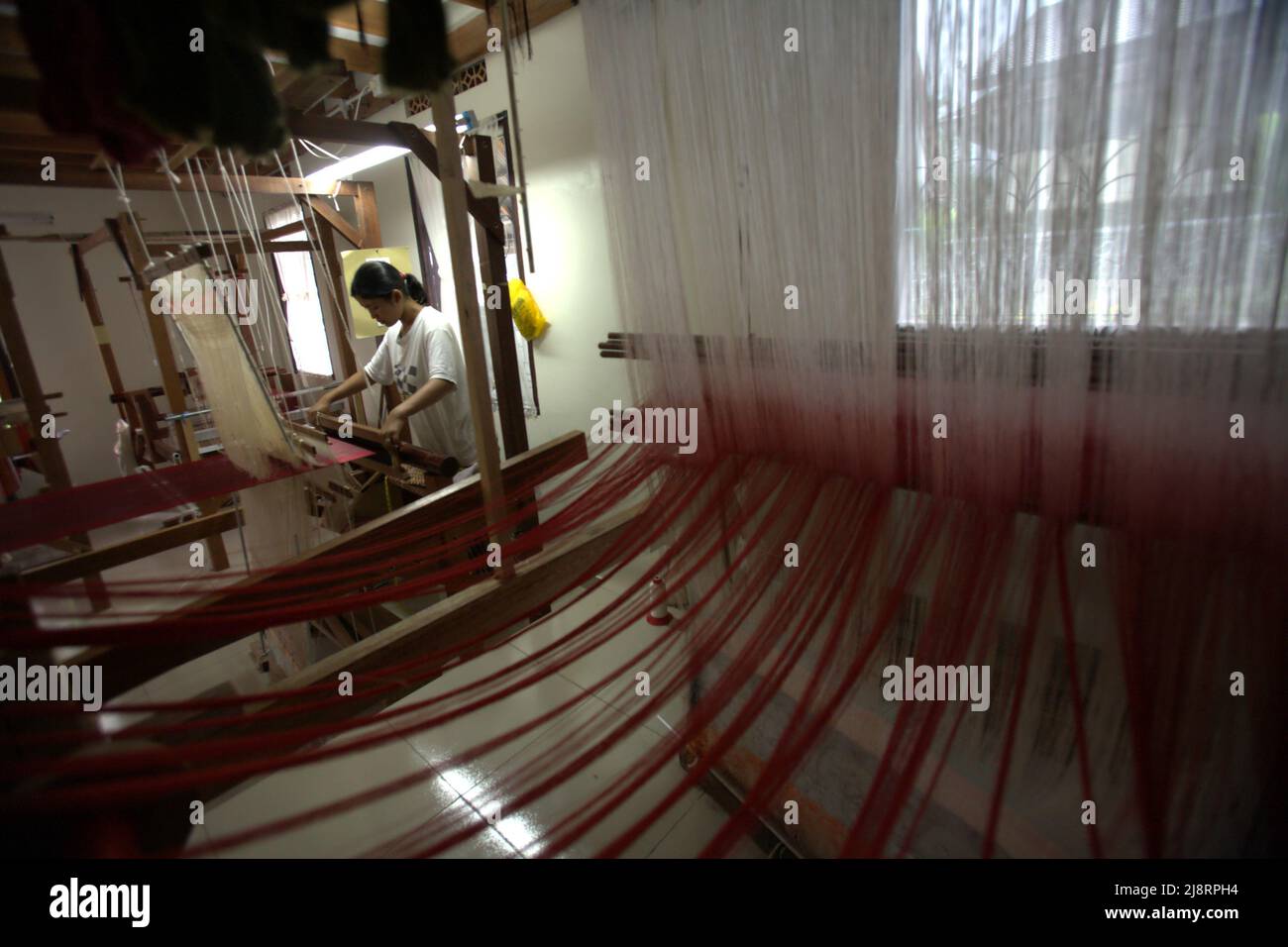 A worker is photographed in a foreground of songket yarns, as she is ...