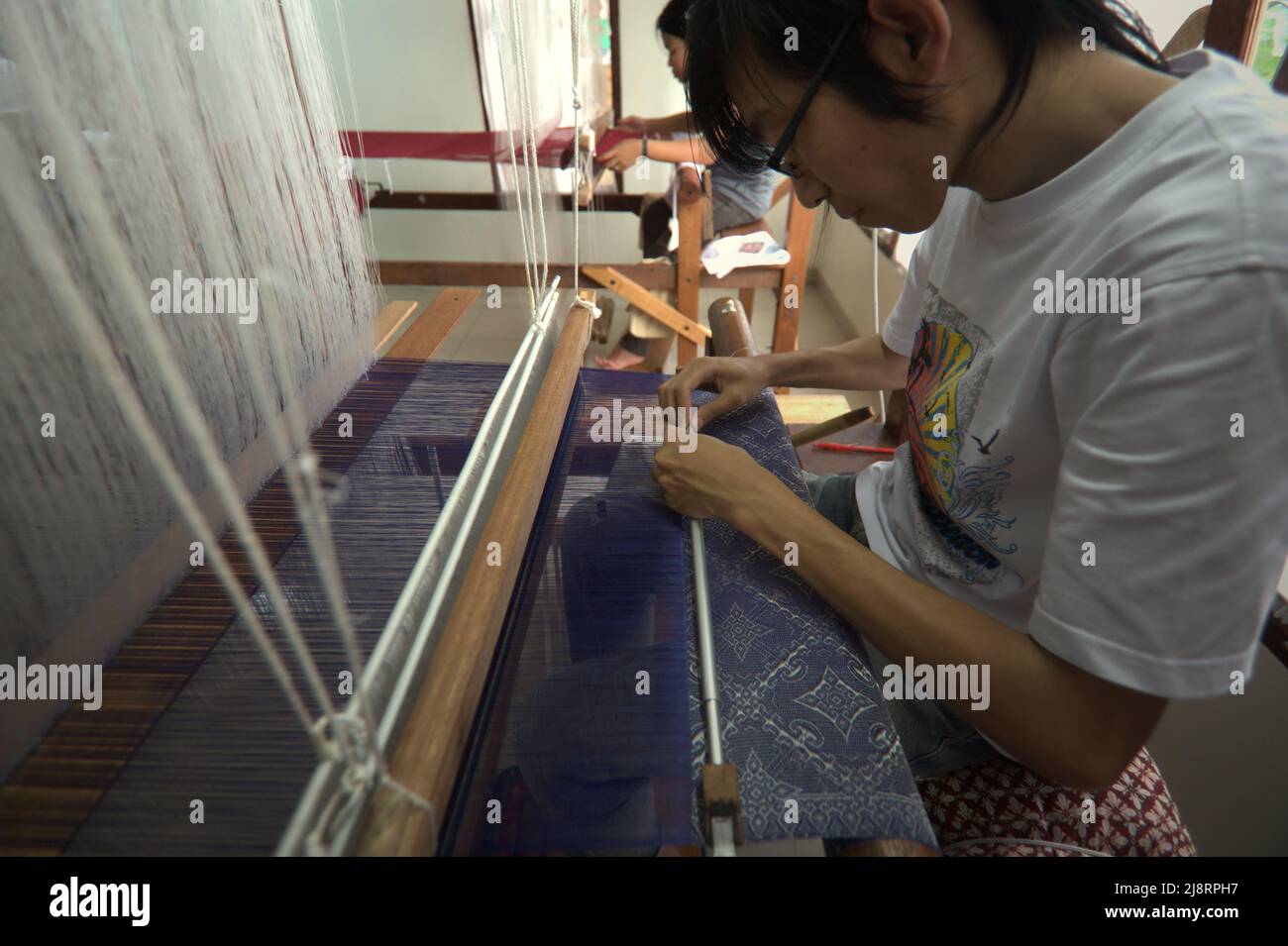 A worker finishing a songket fabric at Erika Rianti songket studio in ...
