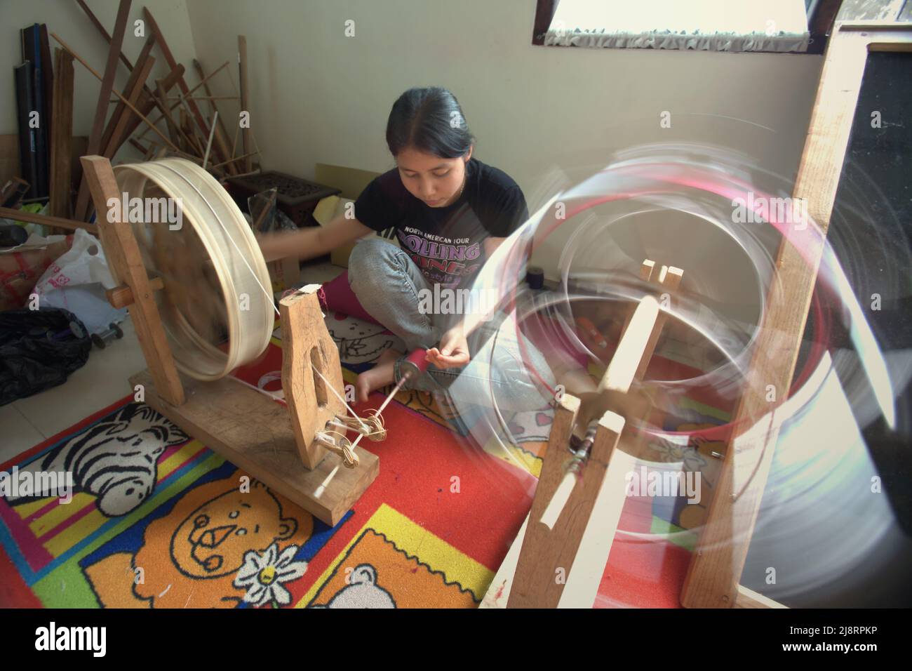 A woman rolling songket yarns at Erika Rianti songket studio in ...