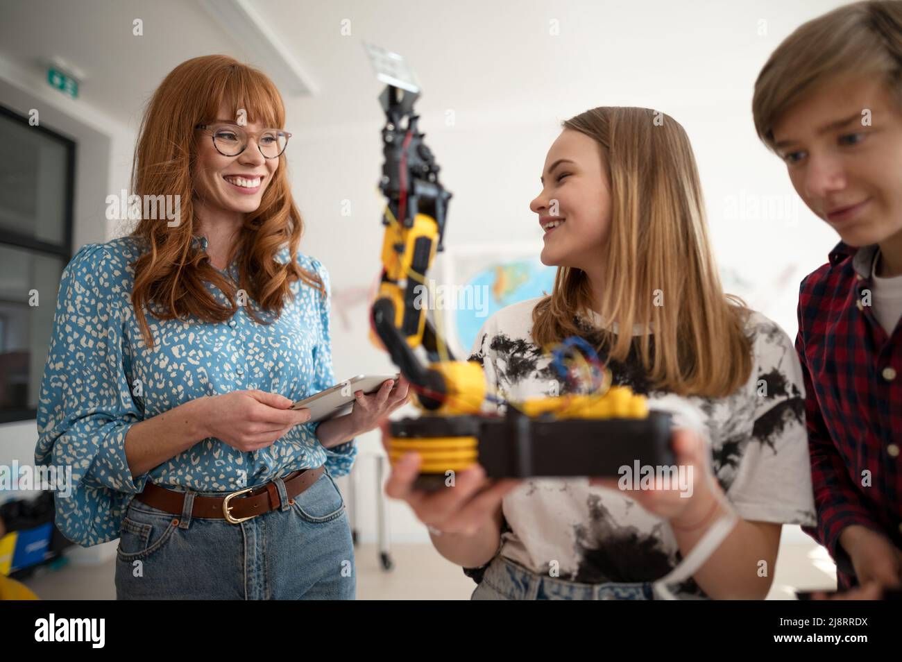 Cheerful students showing their builded robotic toy to young science ...