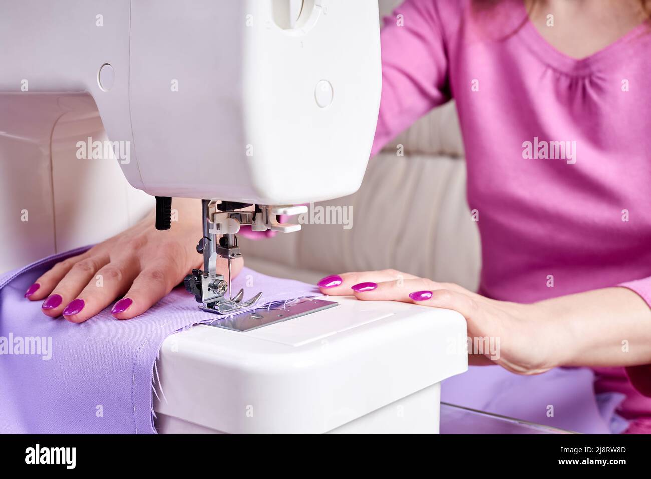 Woman sewing a dress on a sewing machine. Close-up, selective focus ...