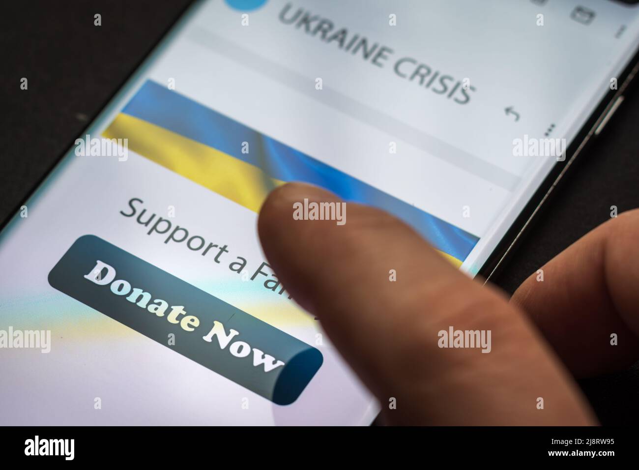 Close-up finger pressing donate icon button on smartphone screen ...