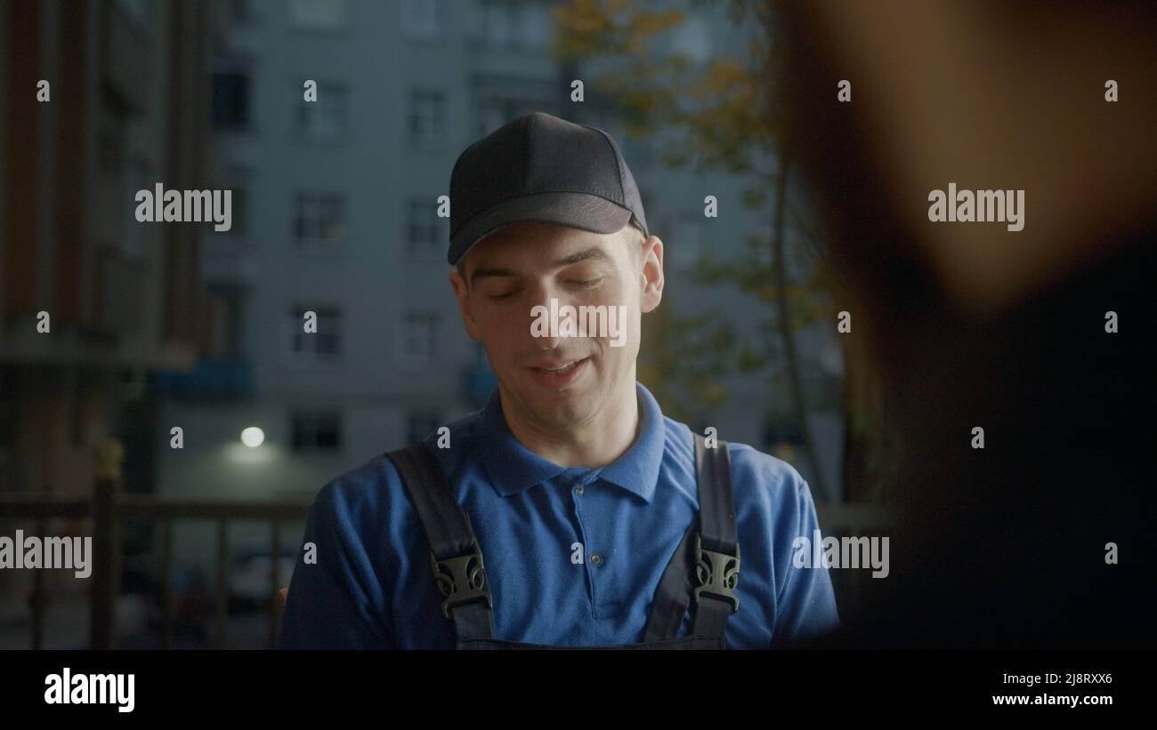 Young delivery man courier in blue cap into customer giving him a ...