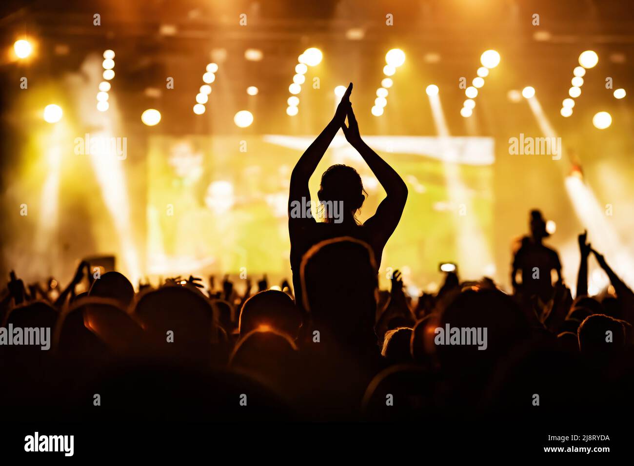 The crowd, happy people enjoying a rock concert, raised up hands and ...