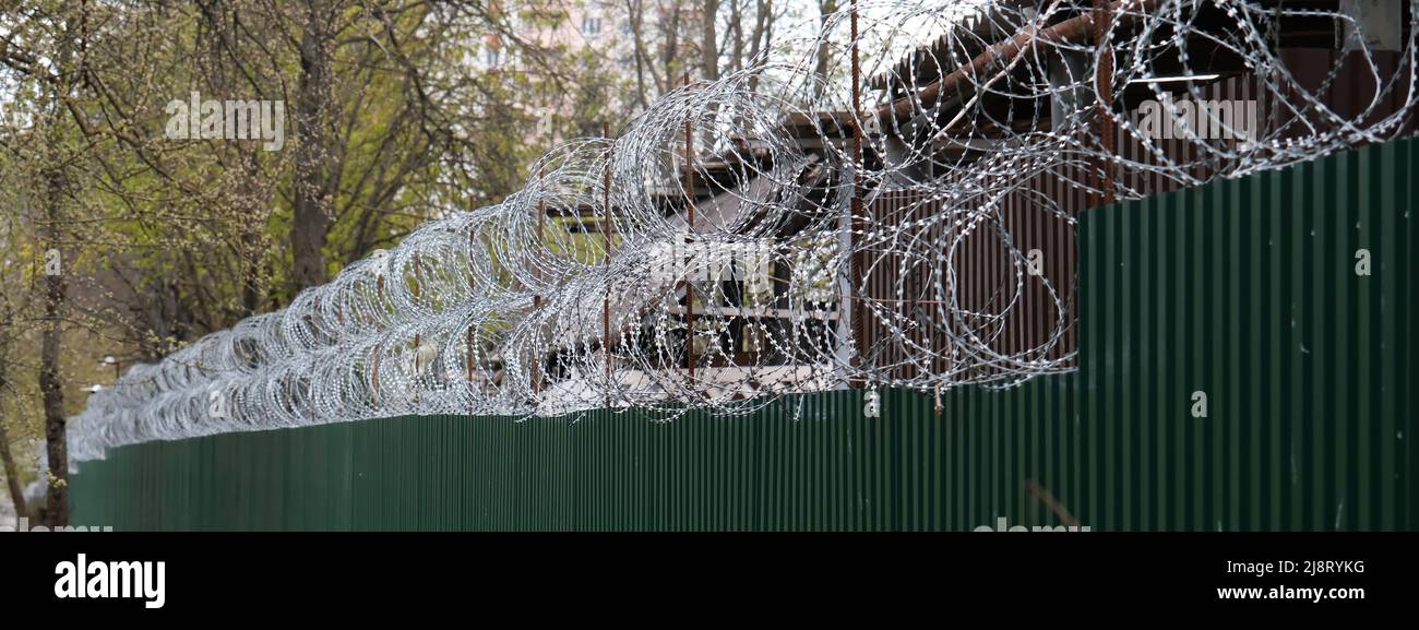 Barbed wire and long green fence, banner photo Stock Photo - Alamy