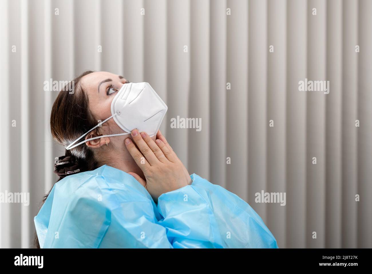 Doctor adjusting Covid-19 N95 mask on her face in admissions office ...