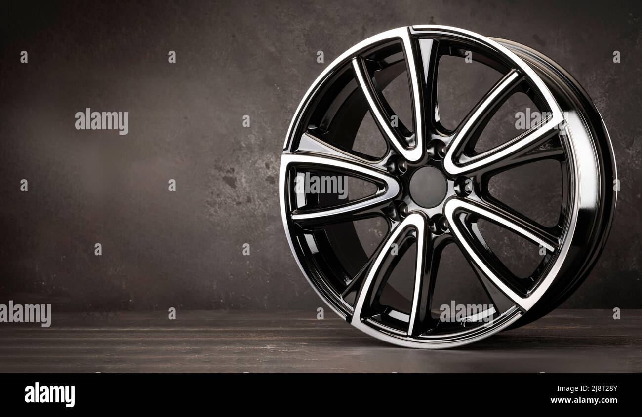 new stylish black alloy wheel on a textured background. aluminum wheel ...