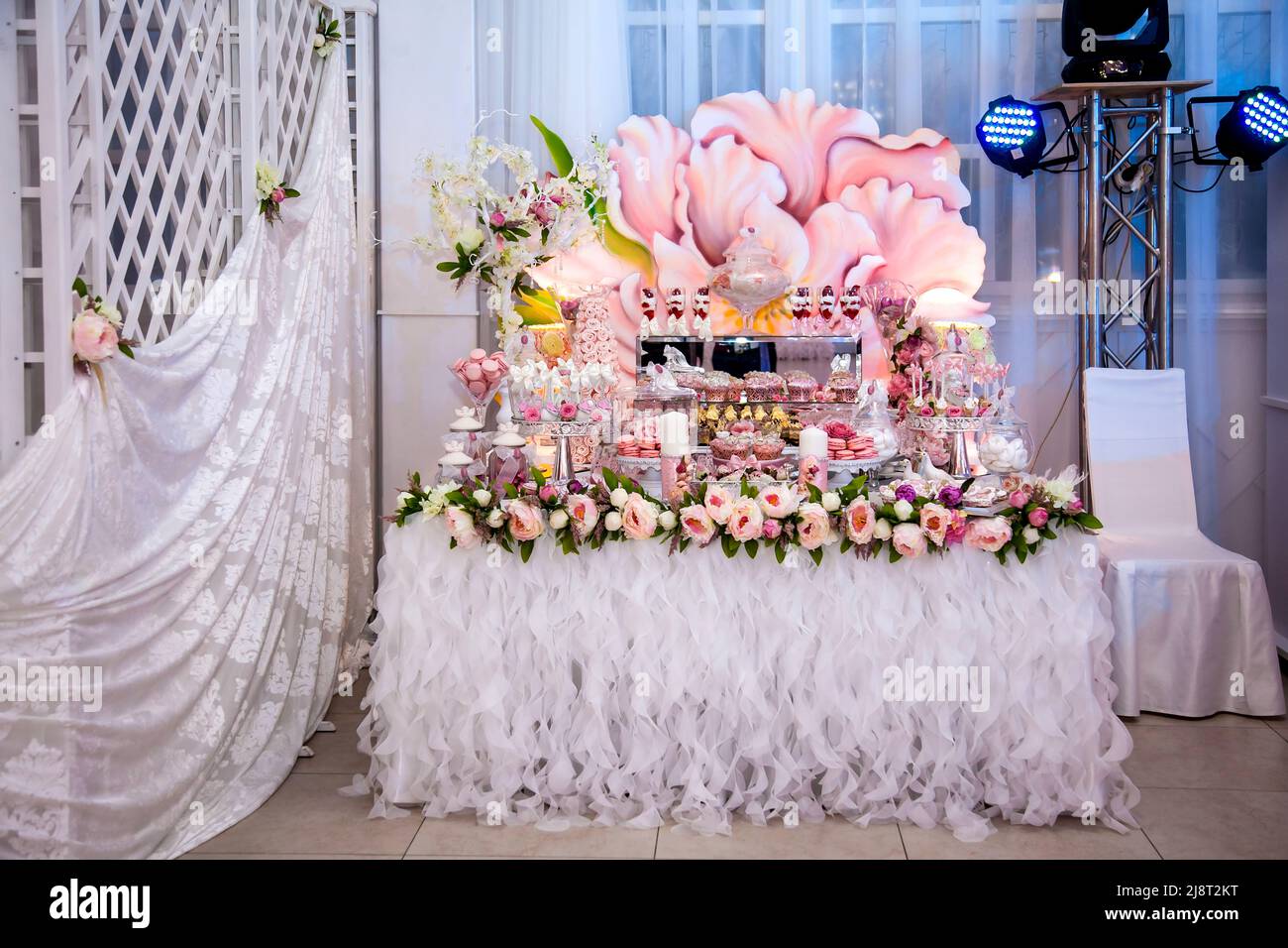 Delicious desserts at the wedding candy bar in the buffet area: decorated candles, rosebuds ...