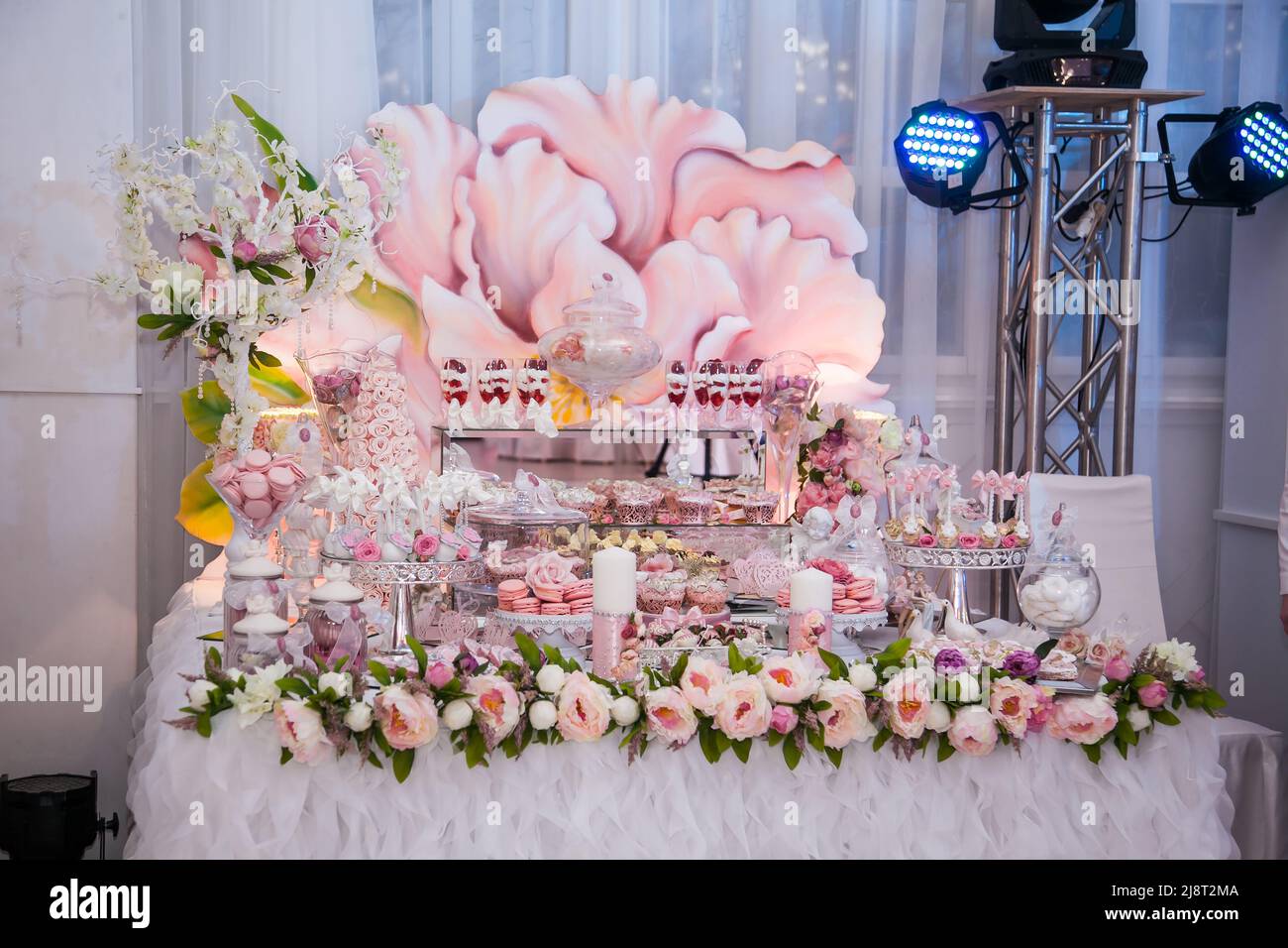 Delicious desserts at the wedding candy bar in the buffet area: decorated candles, rosebuds ...