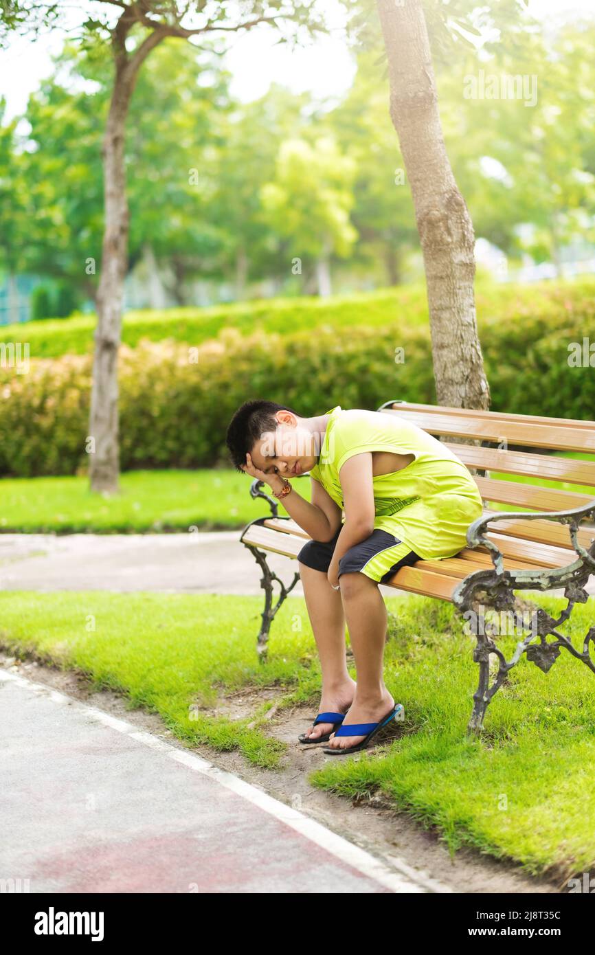 Sport concept - Little sport runner boy sit on the track and take a ...