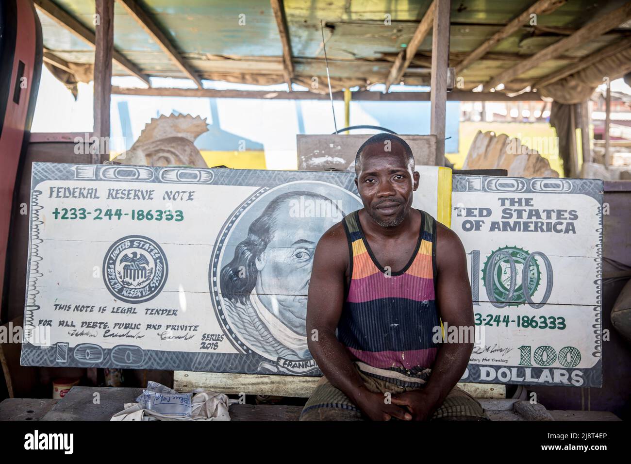 Coffin maker Eric Kpakpo sits in front of a $100 dollar bill-shaped ...