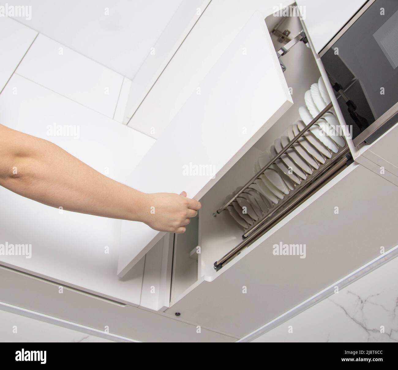 A man opens the door of the kitchen facade with a lifting mechanism ...