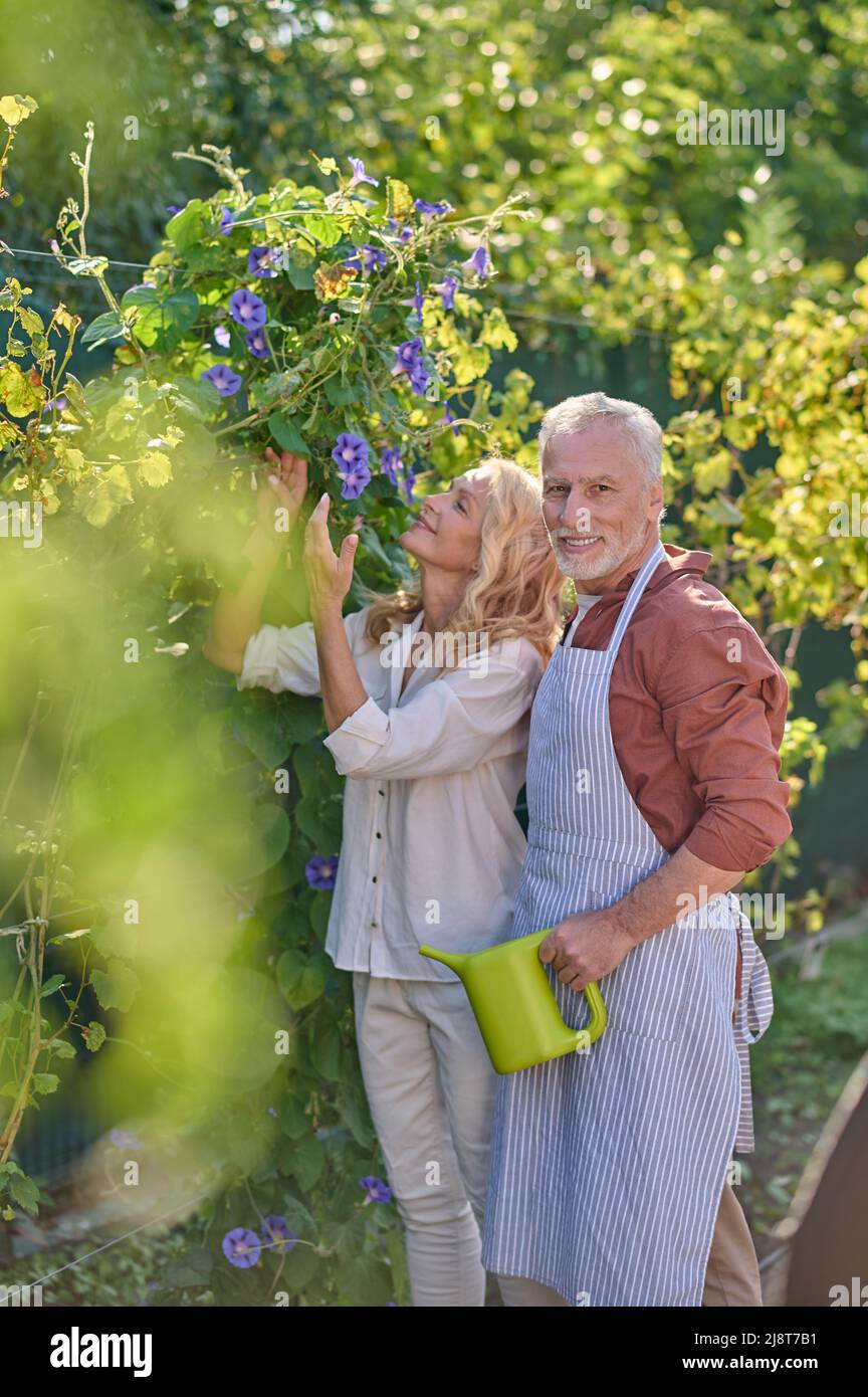 Man hugging woman touching flowers in garden Stock Photo - Alamy