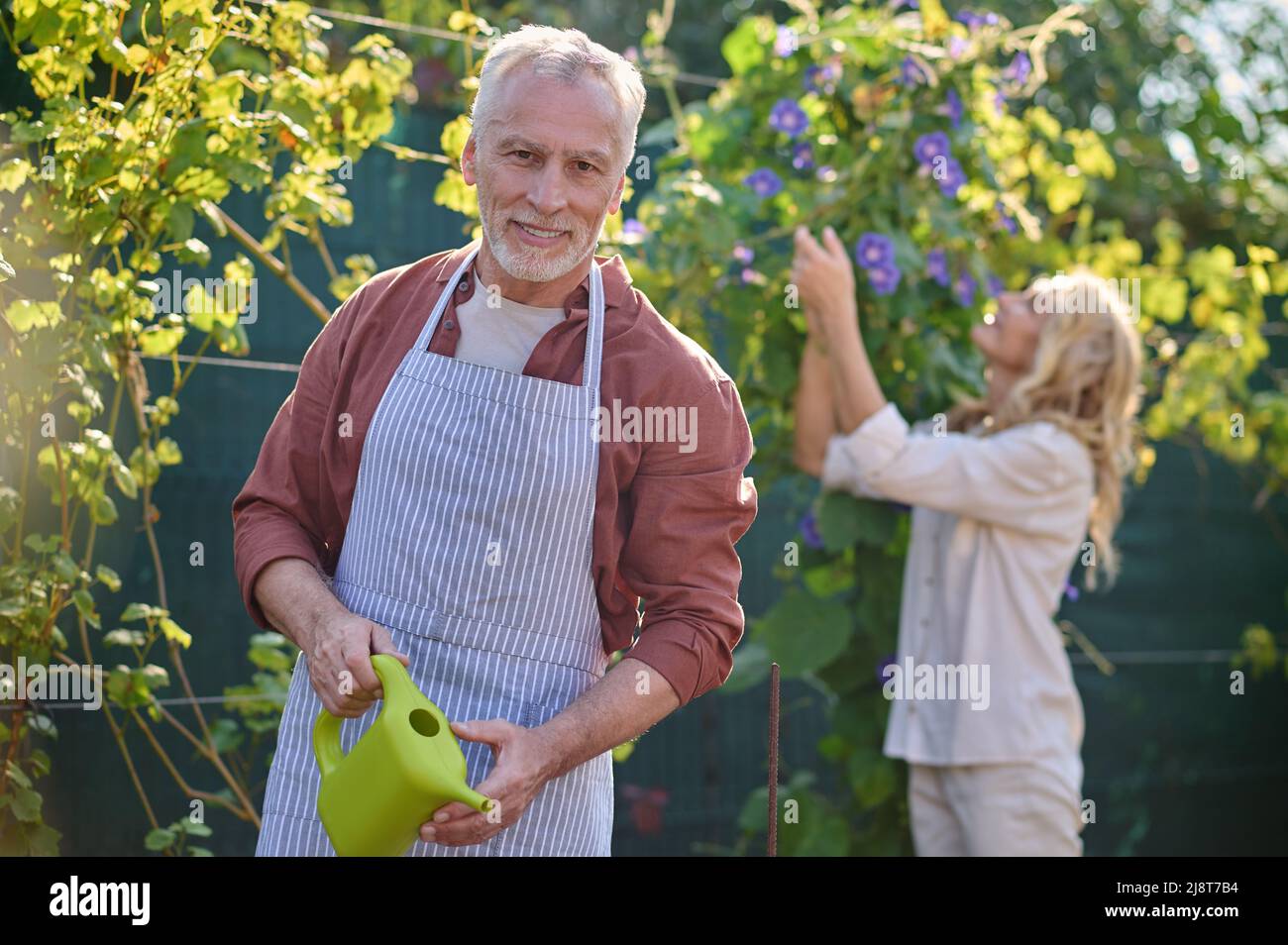 Man looking at camera and woman behind Stock Photo - Alamy