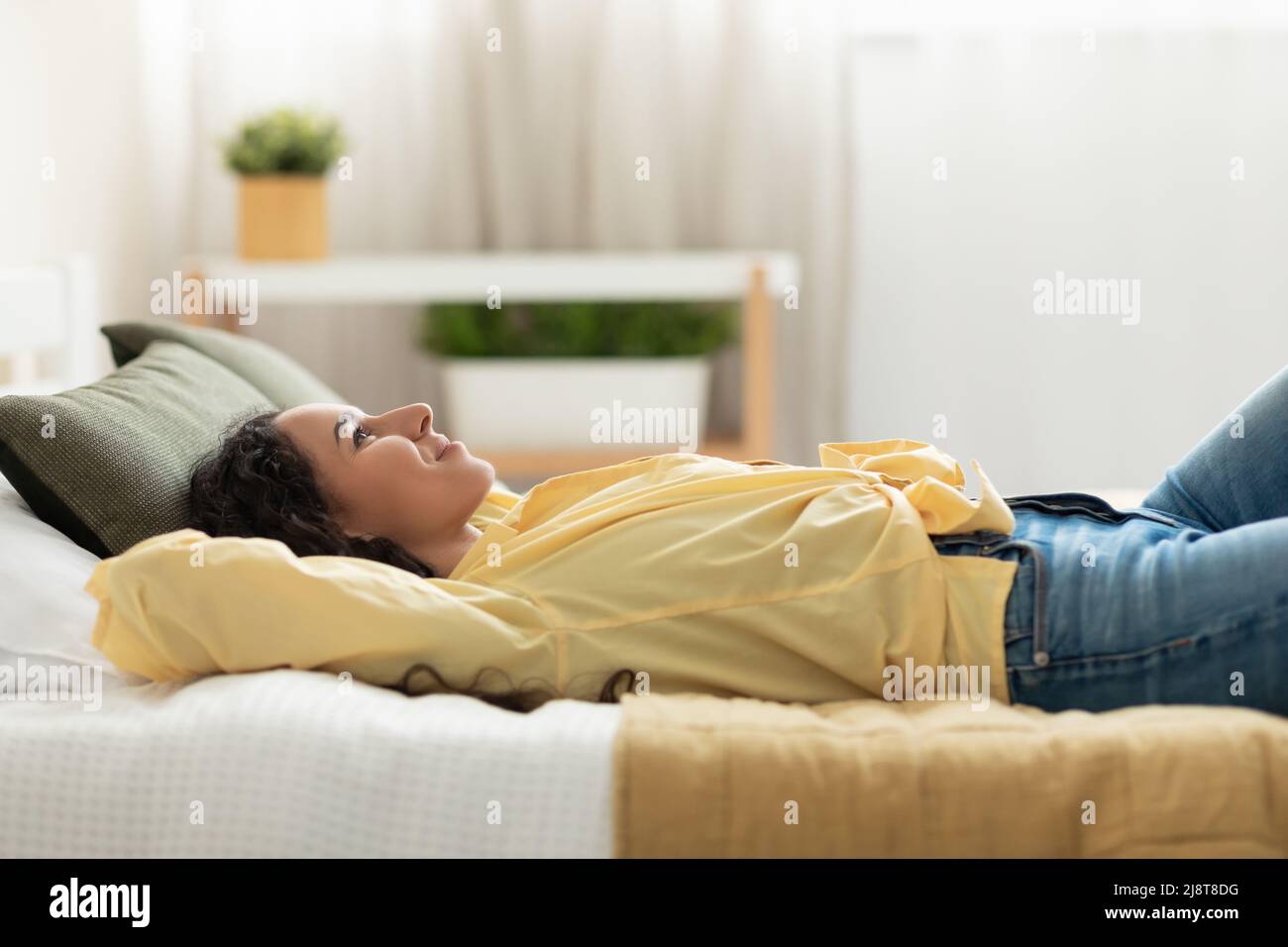 Smiling woman having rest at home lying on bed Stock Photo - Alamy